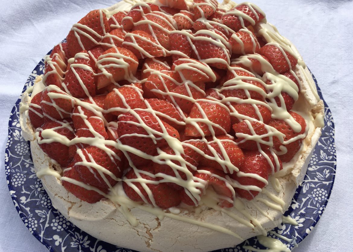 Custard filled pavlova topped with fresh strawberries and white ...